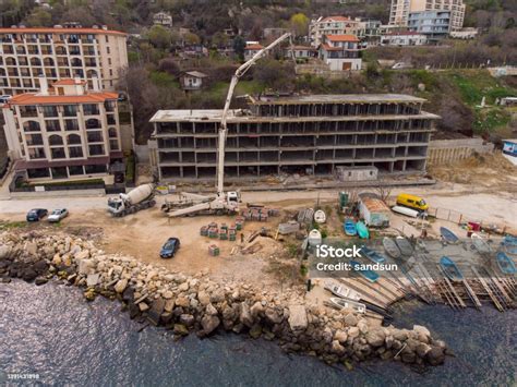 건설중인 주거용 건물의 지붕에 콘크리트 시멘트를 붓고 높은 붐이있는 콘크리트 펌프 트럭 기계를 사용하여 혼합물을 상층에 공급합니다 조감도 0명에 대한 스톡 사진 및 기타