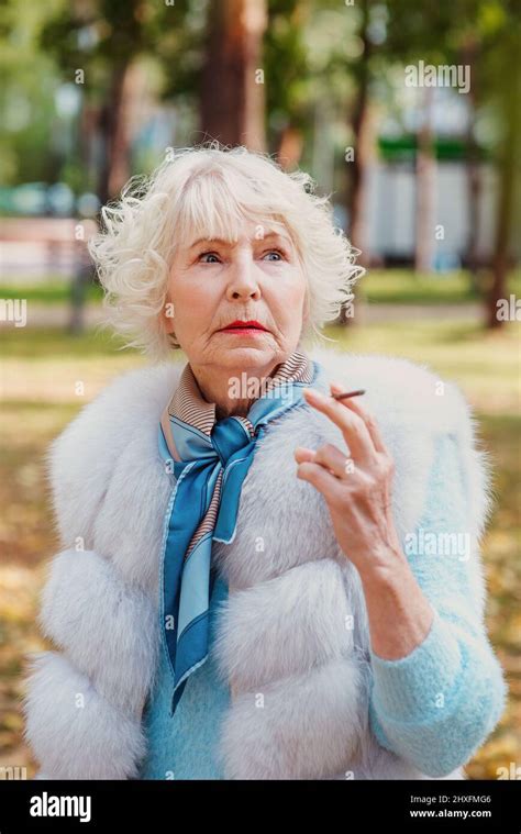 Sad Fashionable Senior Woman With Grey Hair In Fur Coat Outdoor Smoking Cigarette Unhealthy