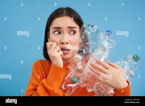 Portrait Of Asian Girl With Scared Face Holding Piles Of Plastic Bottles For Recycling And