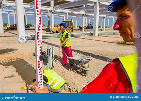 Worker Is Holding Leveling Rod To Measuring Level On Construction Site