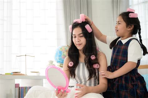 행복한 가족 놀이 시간 엄마를 위한 헤어 스타일을 하는 딸 침대에서 함께 노는 엄마와 아이 가족 개념 아시아 소녀 교복 검은 머리 침실에서 롤 머리 낮