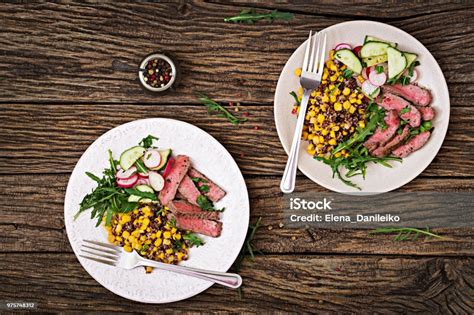 건강 한 저녁 식사입니다 나무 배경에 구운된 쇠고기 스테이크와 노아 옥수수 오이 무와 Arugula 점심 그릇 고기 샐러드입니다 플랫이 하다 상위 뷰 무에 대한 스톡 사진