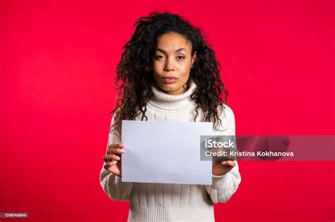 흰색 A4 종이 포스터를 들고 아프리카 머리와 예쁜 혼합 인종 소녀 공간을 복사합니다 빨간 스튜디오 배경에 트렌디 한 여자를 미소 갈색 머리에 대한 스톡 사진 및 기타