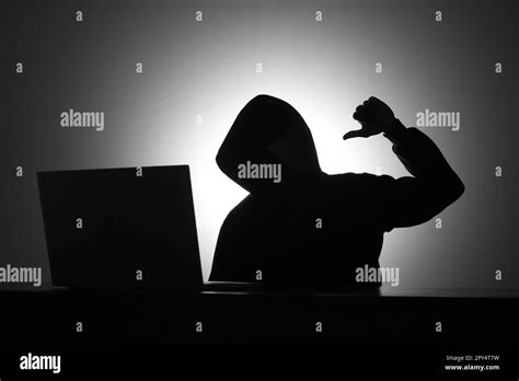 Mysterious Man Wearing Black Hoodie Using Laptop While Mocking Someone
