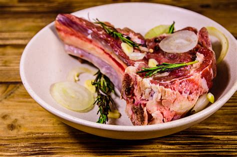 원시 리브아이 스테이크 향신료 로즈마리 양파 마늘을 나무 테이블에 놓은 세라믹 플레이트 갈비 음식에 대한 스톡 사진 및 기타