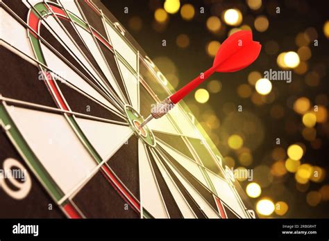 Dart Board With Red Arrow Hitting Target Against Blurred Background Bokeh Effect Stock Photo