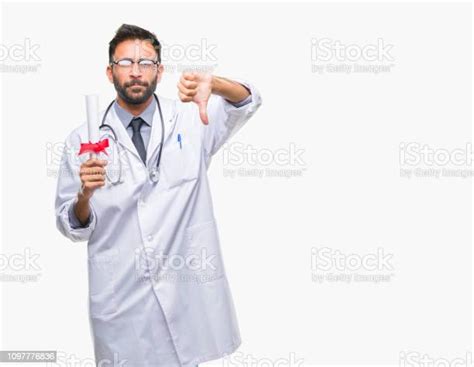 성인 히스패닉 의사 남자와 성 난 얼굴 아래로 엄지 싫어 보여주는 음수 부호 거부 개념 고립 된 배경 위에 학위를 들고 언쟁에