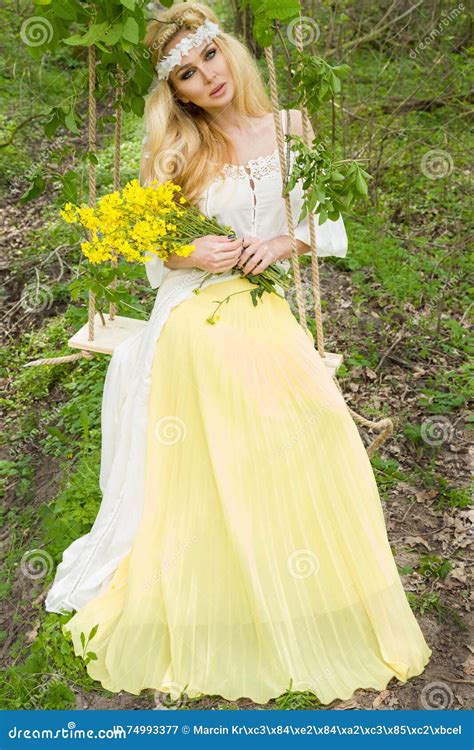 Beautiful Young Sensual Woman Blonde Model Sits In Amazing Dress On A Swing Suspended From The