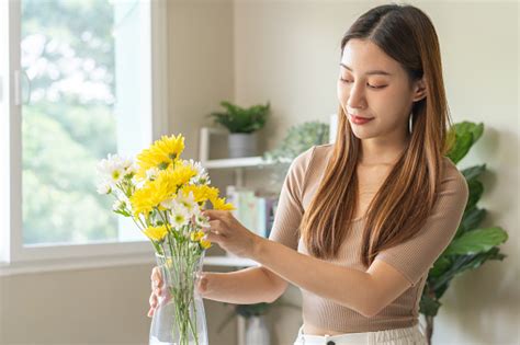 꽃꽂이 행복한 아름다운 아시아 젊은 여성 꽃집 손으로 꽃병에 꽃을 만들고 테이블에 꽃다발을 만들고 거실에 실내 장식을 배치하고