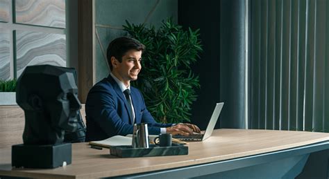 현대 사무실에서 노트북으로 일하는 사업가 일반 관리자 Ceo 양복을 입은 젊은 잘 생긴 자신감있는 남자가 테이블에 앉아있다 경영진 비즈니스 리더 기업가 경력 회계사 은행