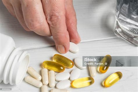 여자 손에 칼슘의 흰색 알 약 글루코사민 보조 제 오메가 3 물과 나무 판자 테이블에 플라스틱 병의 유리의 노란색 캡슐 개념에 대한 스톡 사진 및 기타 이미지 Istock