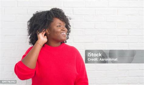 젊은 아프리카계 미국인 플러스 크기 여자 백색 벽돌 벽과 미소에 귀는 청각 소문 또는 험담을 듣고 통해 손을 난청 개념입니다 귀 부분에 대한 스톡 사진 및 기타 이미지