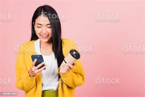 행복한 아시아 초상화 아름다운 귀여운 젊은 여자 흥분 흥분 미소 들고 휴대 전화와 커피 가서 스튜디오 촬영 분홍색 배경에 고립