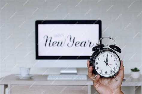 Premium Photo Hand Holding Alarm Clock Countdown With Happy New Year Text On Computer Screen