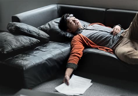 原稿を持ってソファーで寝落ちする担当の男性｜ぱくたそフリー素材