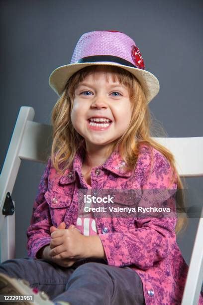 모자를 쓴 어린 소녀 미소와 웃음 회색 배경 핑크 셔츠와 회색 바지 어린 시절은 유쾌하게 전달됩니다 건강한 생활방식에 대한 스톡 사진 및 기타 이미지 Istock