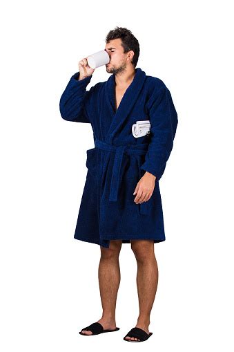 졸린 젊은 남자 지저분한 머리의 전체 길이 초상화 푸른 목욕 가운을 입고 손에 아침 신문을 들고 자신의 컵에서 커피를 마시는 흰색 배경에 고립 남자에 대한 스톡 사진 및