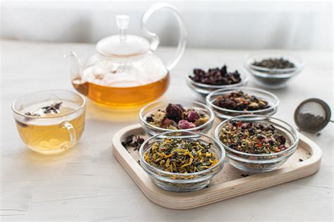 뜨거운 차와 밝은 테이블에 주전자와 유리 컵 은 흰색 배경에 허브 차의 다른 종류와 창 트레이에 의해 면역력을 강화하기 위해 맛