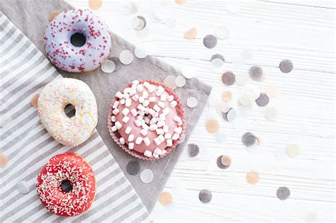 뿌리와 마 시 멜로와 함께 맛 있는 다채로운 도넛 색종이 평평한 누워 복사 공간이 있는 세련 된 흰색 테이블에 있습니다 파티