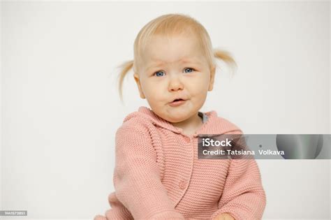 흰색으로 고립 된 불행한 어린 소녀 스튜디오에서 슬픈 아이의 초상화 분홍색 니트 스웨터에 불만스러운 표정을 가진 금발 머리 아이 아름 다운 아이 개념입니다 유년 시대 울음에