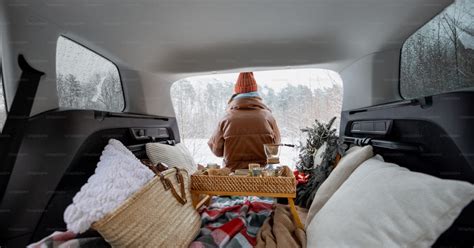 소나무 숲 근처의 자동차 트렁크에 앉아 겨울 방학 동안 자동차로 여행하는 여자 뒷면에서 본 모습 고품질 사진 사진 Unsplash의 백인 이미지