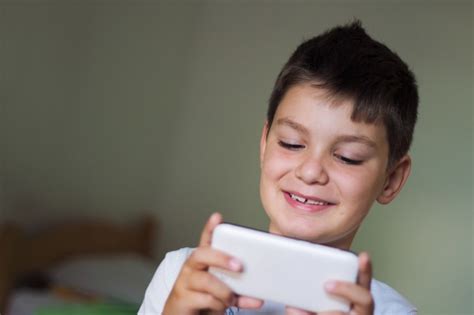 Ребенок, используя мобильный смартфон и улыбающийся | Бесплатно Фото