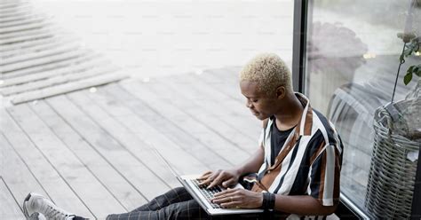집에서 나무 테라스에서 노트북 컴퓨터를 사용하는 흑인 여가의 개념 현대 국내 생활 방식의 아이디어 젊고 집중하고 쉬는 사람 여름 화창한 낮 사진 Unsplash의