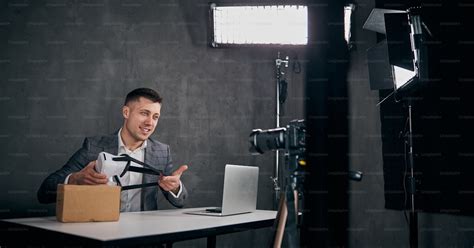 Vr 안경을 들고 노트북을 들고 테이블에 앉아 브이로그를 위한 비디오를 촬영하는 동안 웃고 있는 잘생긴 남성 블로거 사진 Unsplash의 남자 이미지