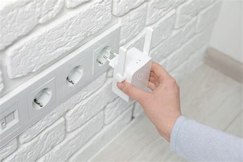 Woman Inserting Wireless Wi Fi Repeater Into Power Socket Indoors