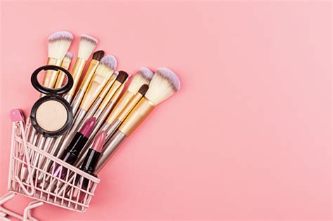 분홍색 배경에 화장품 미니 식료품 카트에 립스틱 하이라이터 및 메이크업 브러쉬 럭셔리 장식 화장품 플랫 레이 상단보기 모형 템플릿의 집합입니다 쇼핑 컨셉 0명에 대한 스톡