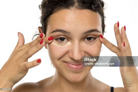 눈 밑에 컨실러를 바르고 웃고 있는 젊은 여자 뷰티 루틴 중 행복한 표정 클로즈업 스튜디오 초상화 흰색 배경에 스킨 케어 응용 프로그램 강조 표시 20 24세에 대한 스톡