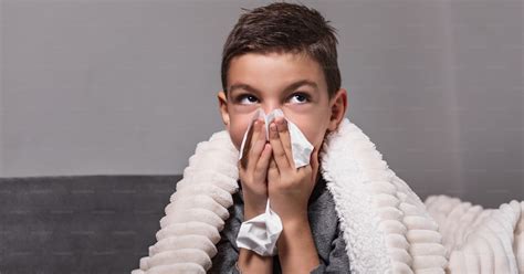 감기와 독감 아픈 소년의 초상화는 감기에 걸렸고 아프고 종이 닦음에 재채기를 했습니다 담요로 코를 닦는 어린 건강에 해로운 아이의 클로즈업 의료 개념입니다 사진