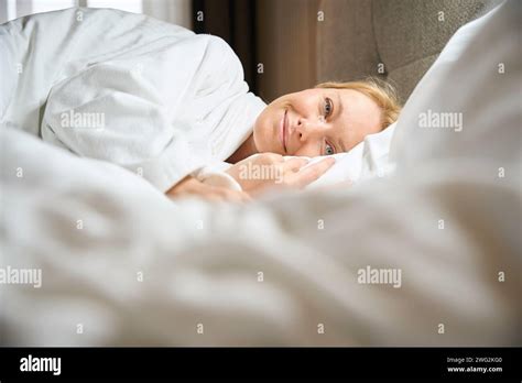 Pleased Young Female Is Luxuriating In Bedroom After Morning Awakening