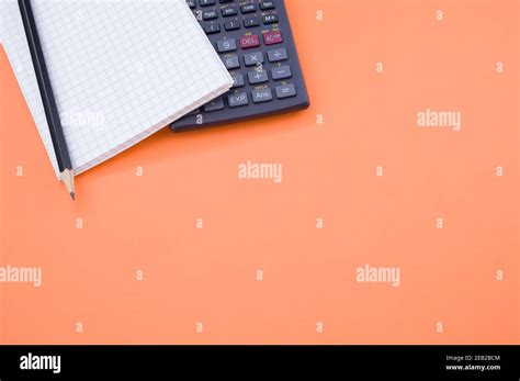 A Scientific Calculator Notepad And Pencil On Orange Background With
