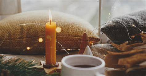 따뜻한 차 한잔 크리스마스 조명 소나무 촛불 창문의 베개를 배경으로 크리스마스 별을 조명했습니다 스칸디나비아 겨울 휘게 아늑한 숙소 분위기 있는 마법의 순간