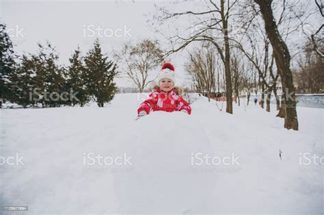 쾌활 한 작은 소녀 겨울 따뜻한 옷과 모자 눈덩이 놀고 눈 덮인 공원이 나 숲 야외에서 눈사람 만들기 겨울 재미 휴일에 여 가입니다 사랑 관계 가족 라이프 스타일 개념입니다