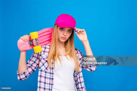 멋진 자신감의 초상화 닫고 심각한 여 자가 여기에 어깨와 터치 캡에 스케이트 보드를 들고 캐주얼 복장을 했다 파란색 배경에 고립 된 젊은 여자의 이미지 스케이트보드에 대한