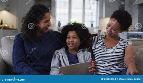 Smiling Mixed Race Lesbian Couple And Daughter Using Digital Tablet On