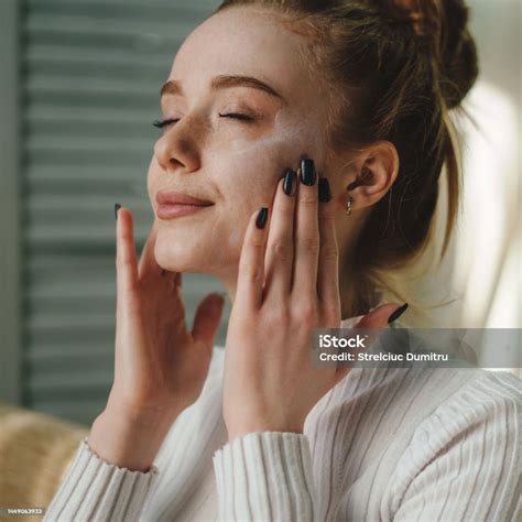 그녀의 얼굴에 얼굴 크림을 바르는 완벽한 신선한 피부를 가진 젊은 주근깨 여성의 초상화 스파와 웰빙 스킨 케어 개념 클로즈업