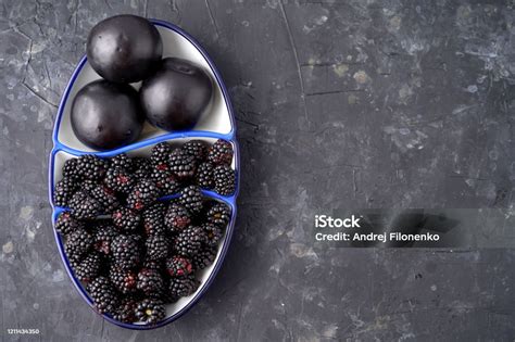 다크 스톤 표면에 깊고 타원형 접시에 블랙 베리와 신선한 잘 익은 유기농 검은 자두 텍스트 상단보기 장소 다이어트 식품 비건