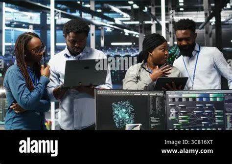 Portrait Of Smiling Data Center Specialists Collaborating In Server