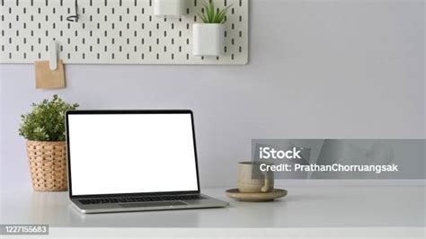 흰색 빈 화면 컴퓨터 노트북의 사진은 배경으로 편안한 거실 흰색 벽 위에 커피 컵과 고리버들 바구니에 공장으로 둘러싸인 흰색 작업 책상에 넣어 0명에 대한 스톡 사진 및