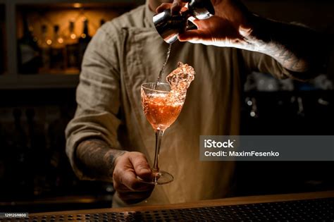 남성 바텐더는 칵테일 잔을 들고 알코올 음료를 마시고 지거에서 액체를 추가합니다 물이 튀는에 대한 스톡 사진 및 기타 이미지