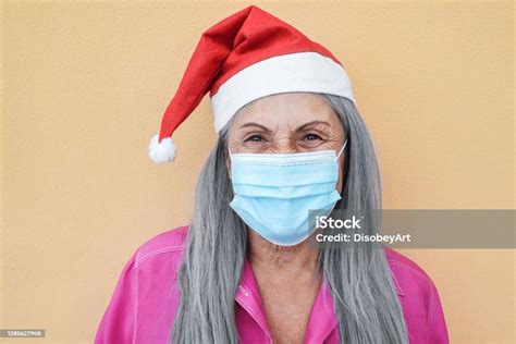 보호 얼굴 마스크와 크리스마스 모자를 착용 행복 한 노인 여자 얼굴에 초점 산타 클로스에 대한 스톡 사진 및 기타 이미지 산타 클로스 코로나바이러스 12월 Istock