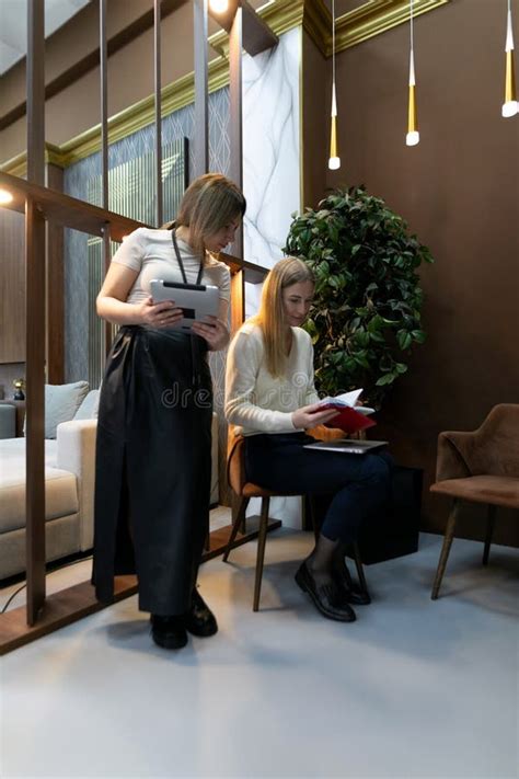 Two Women Collaborating In A Modern Office Space With Creative Decor And Natural Lighting During