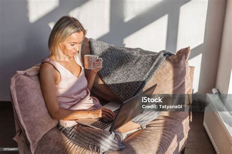 차 또는 커피 한 잔과 함께 거실에서 소파에 앉아있는 행복한 꿈꾸는 중년 여성 40 44세에 대한 스톡 사진 및 기타 이미지 40 44세 거실 고름 Istock
