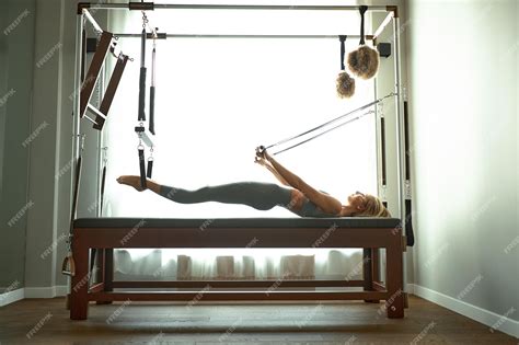 Premium Photo | The instructor does exercises on the reformer a ...