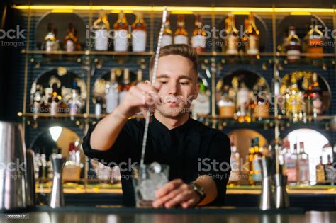 바텐더 남성 교반 얼음 큐브의 초상화는 다른 알코올 음료와 선반의 배경에 바 카운터에 서 숟가락을 사용하여 유리에 저어 각얼음에 대한 스톡 사진 및 기타 이미지 Istock