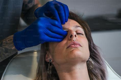Young Woman Getting Her Ear Pierced Man Showing A Process Of Piercing