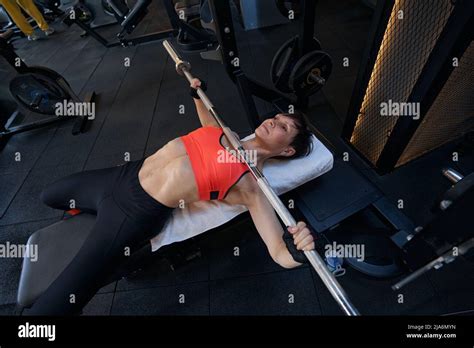 Professional Sportswoman Bench Pressing During Workout At Gym Stock